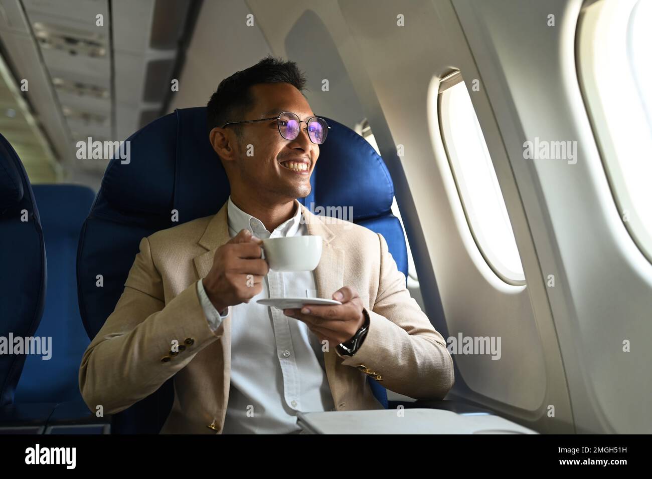 Positive businessman passenger drinking coffee from paper cup while ...