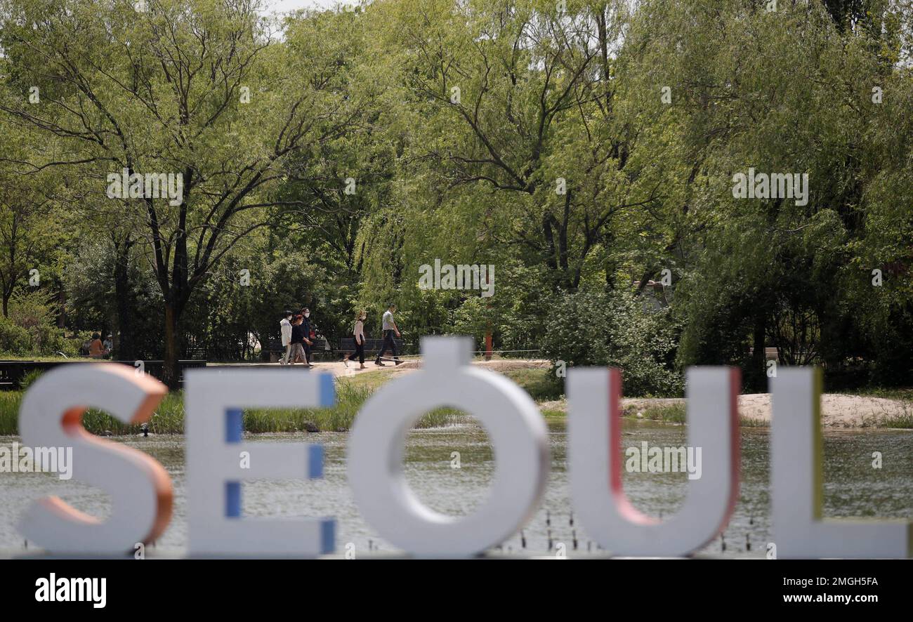 Visitors wearing face masks walk at a park in Seoul, South Korea ...