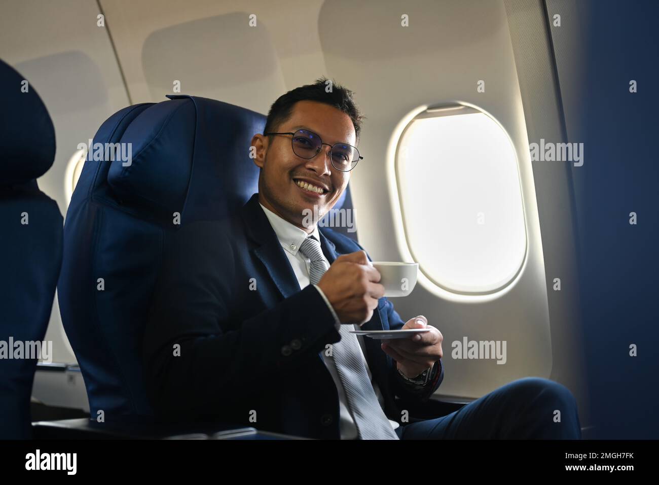 Positive businessman passenger drinking coffee from paper cup while ...