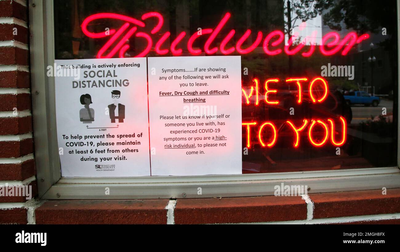 A "social distancing" sign is shown on the window of Cheers to You bar ...