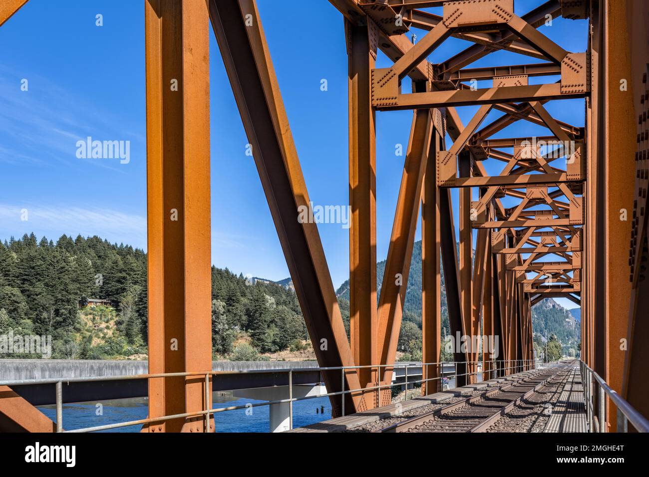 Rusty narrow metal truss railway transportation bridge across Columbia ...