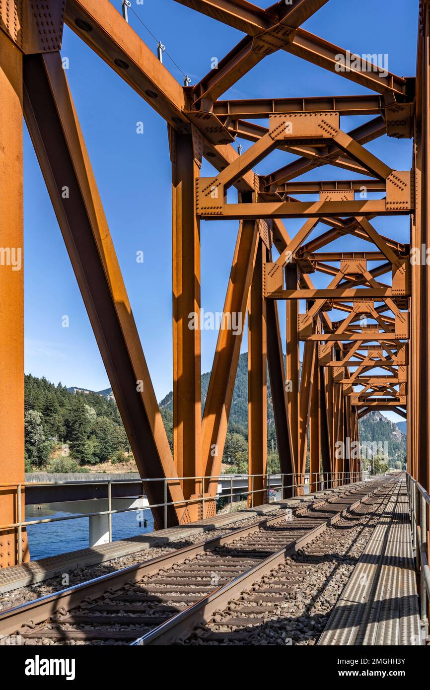Rusty narrow metal truss railway transportation bridge across Columbia ...