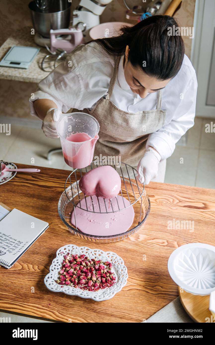 Female baker make Perfect custom pink heart shape cake in kitchen ...