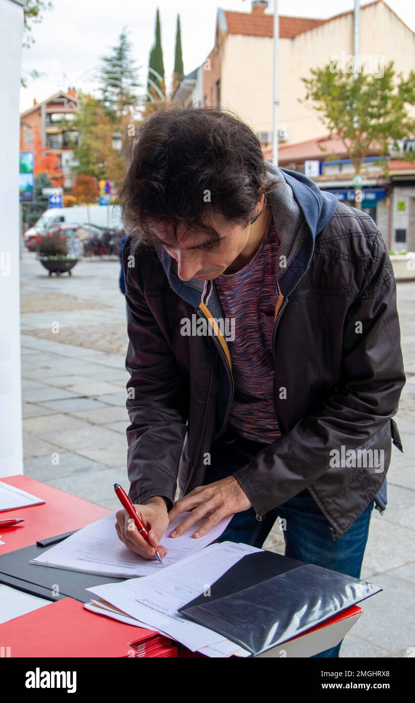 Young adult man filling out a form on the street. Signature petition ...