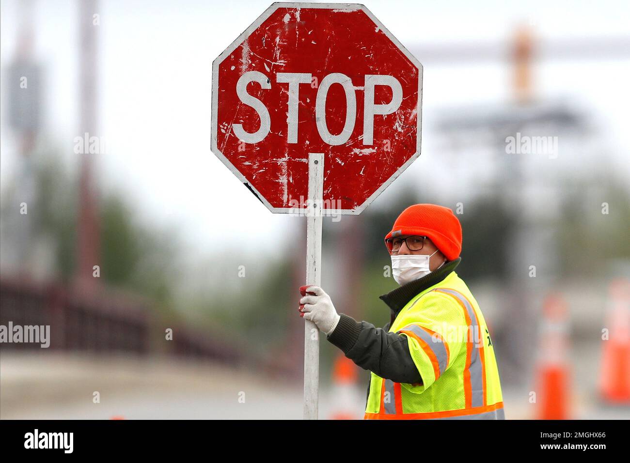 A construction worker helps direct one-way traffic as colleagues work ...