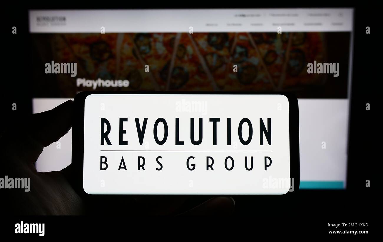 Person holding cellphone with logo of hospitality company Revolution ...
