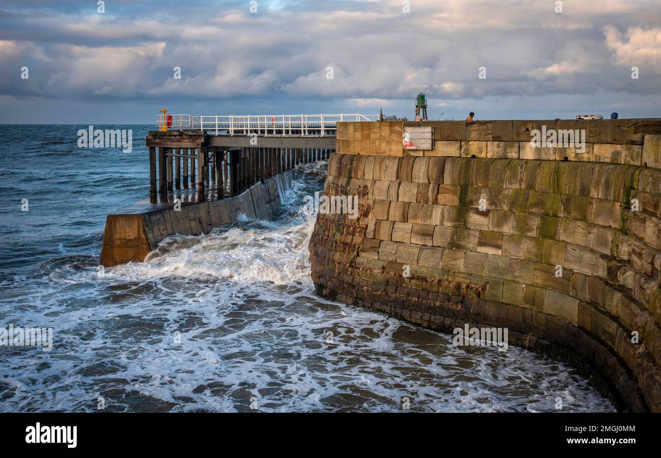 Large waves crash through the harbour entrance piers at Whitby, North ...