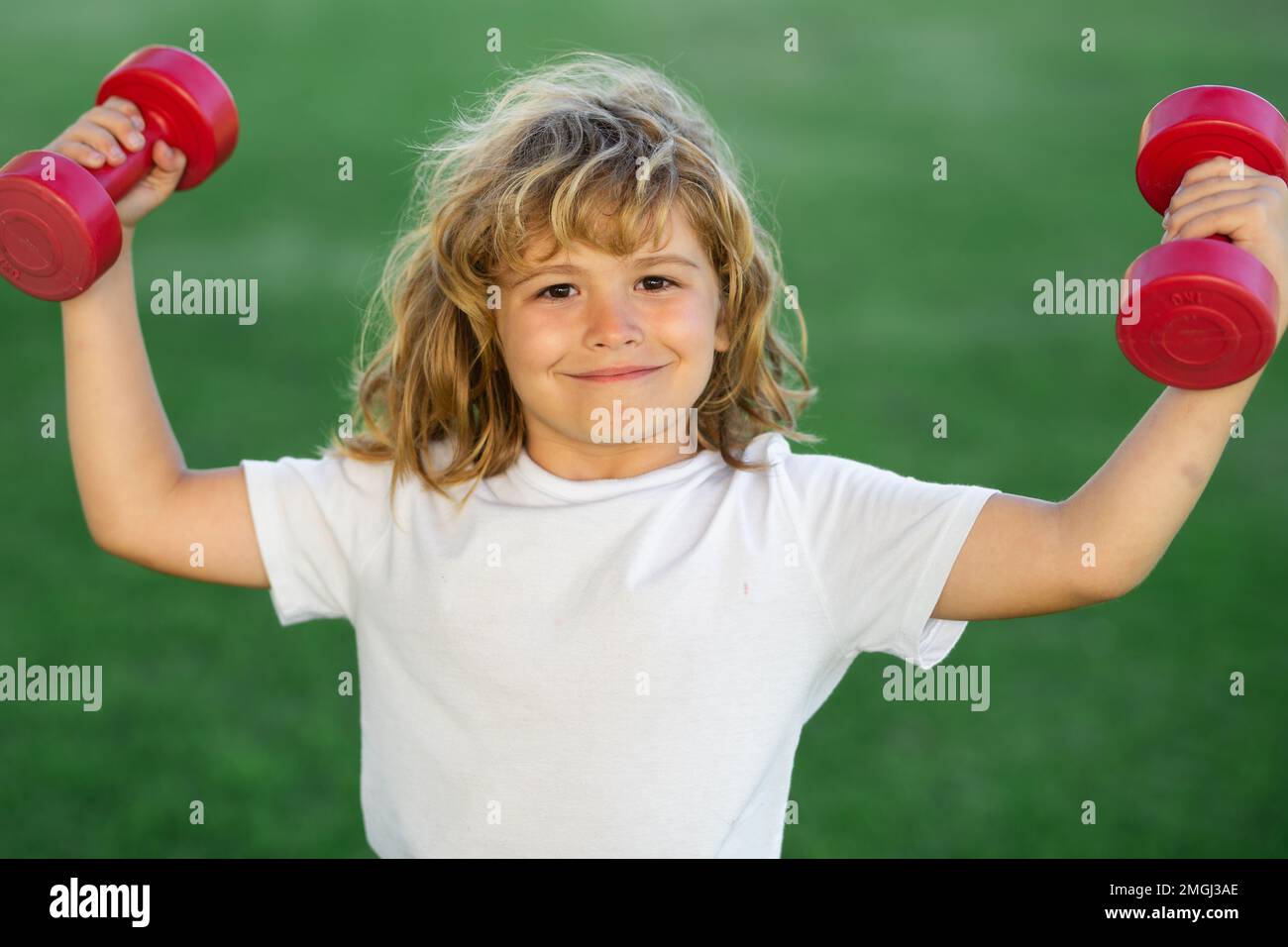 Summer sport. Child boy raising a dumbbell. Cute child training with ...