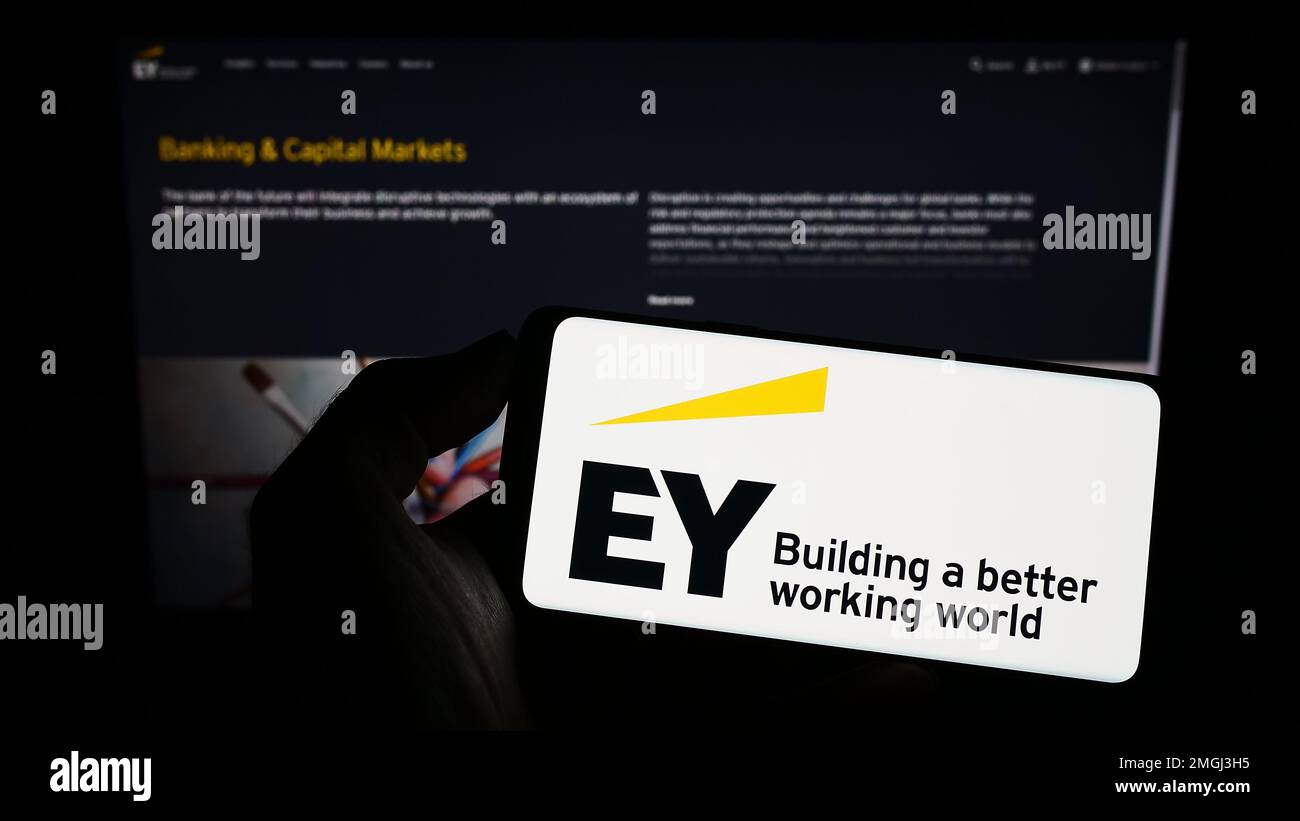 Person holding mobile phone with logo of company Ernst Young Global ...