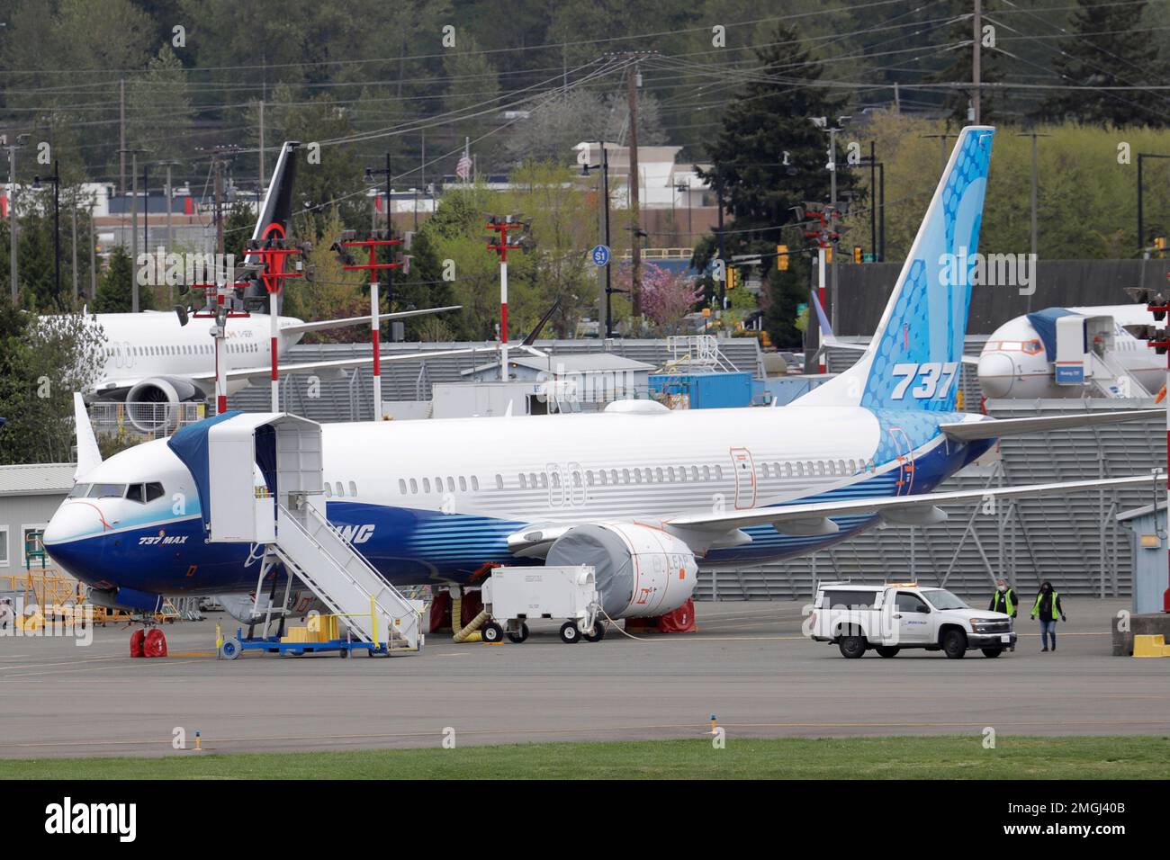 Boeing Co. workers wearing masks walk near a 737 Max airplane, Tuesday ...