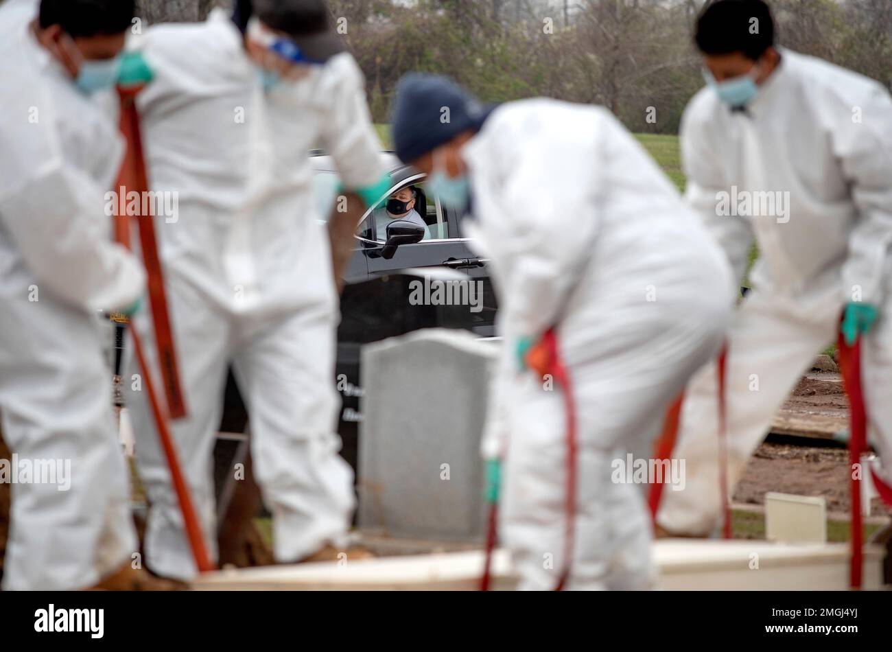 Gravediggers lower the casket of David Tokar, as his son, Michael Tokar ...