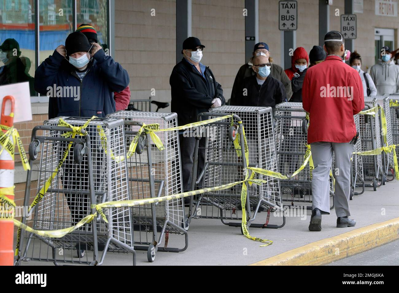 People wear mask as they wait safely distanced in line to enter a ...