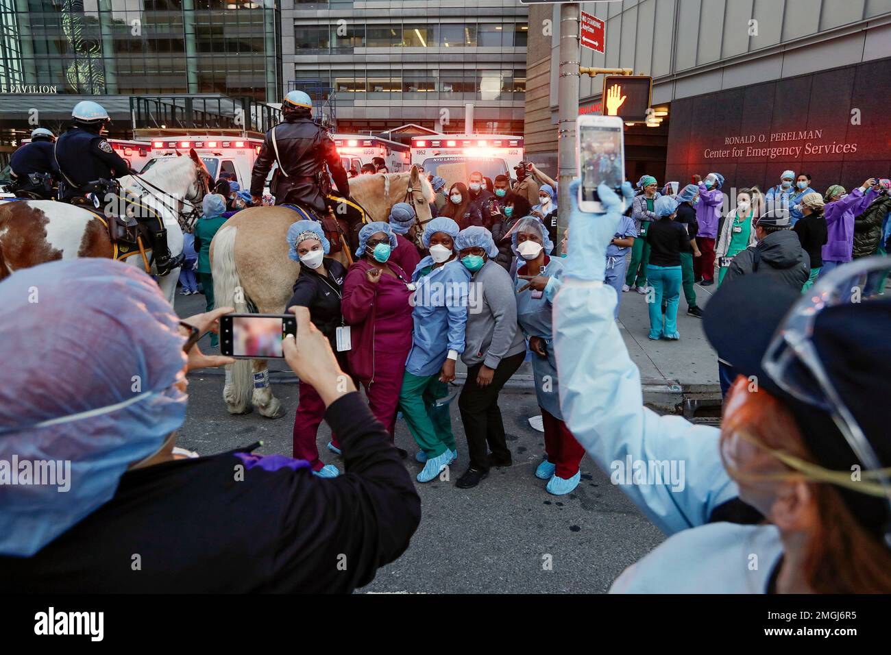 Medical workers pose for photographs as police officers and pedestrians cheer for them outside ...
