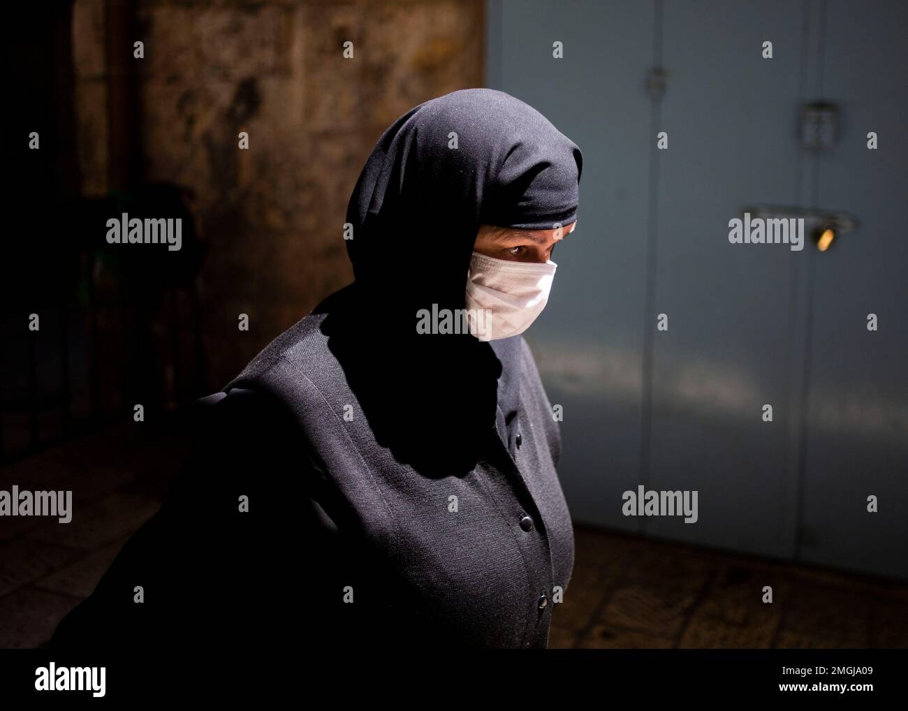 A nun wears a mask walks towards the Church of the Holy Sepulchre ...