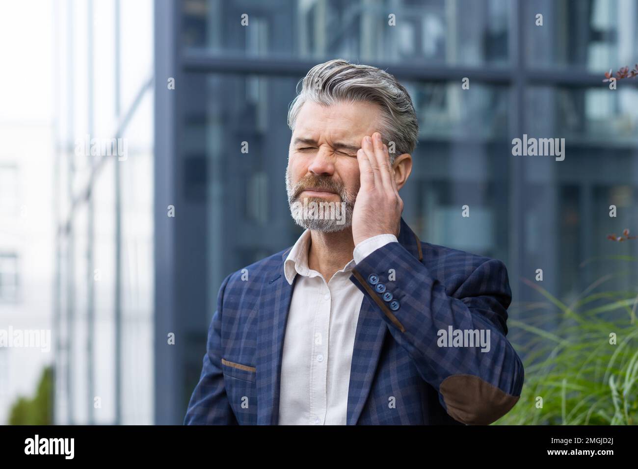 Sick and sad mature businessman outdoors sitting on bench on office ...