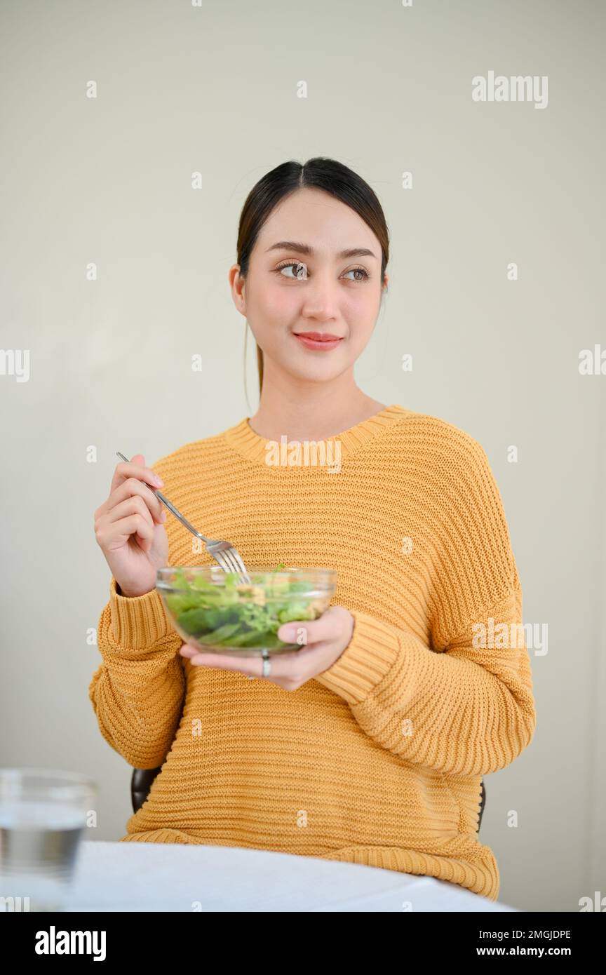 Portrait, Gorgeous millennial Asian woman in comfy clothes holding a ...