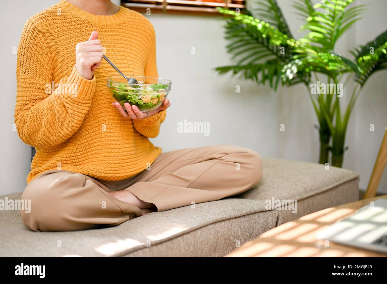 Healthy woman in casual comfy clothes holding a salad bowl, eating ...