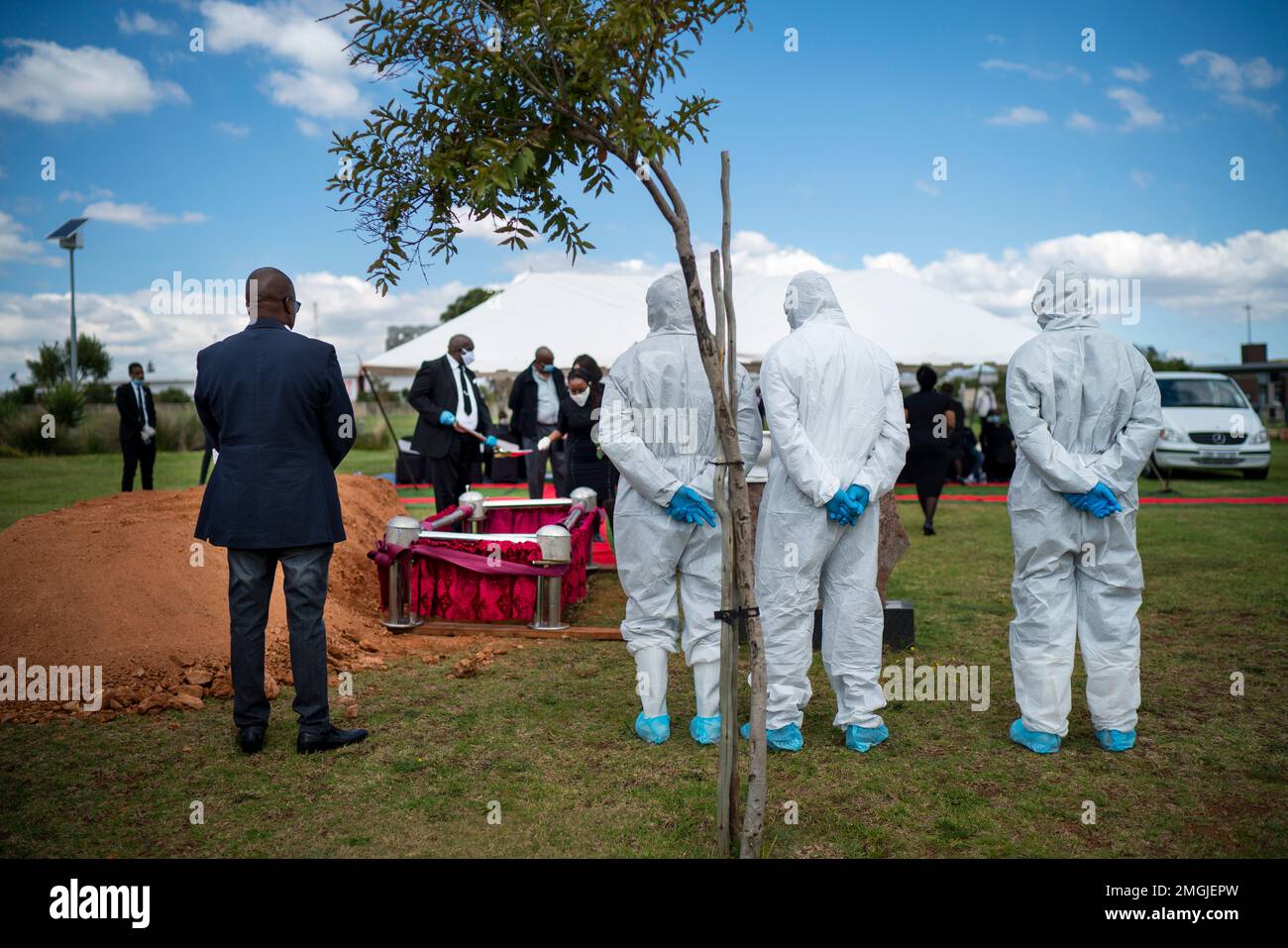 Pallbearers wearing full PPE stand behind the grave of Benedict Somi ...