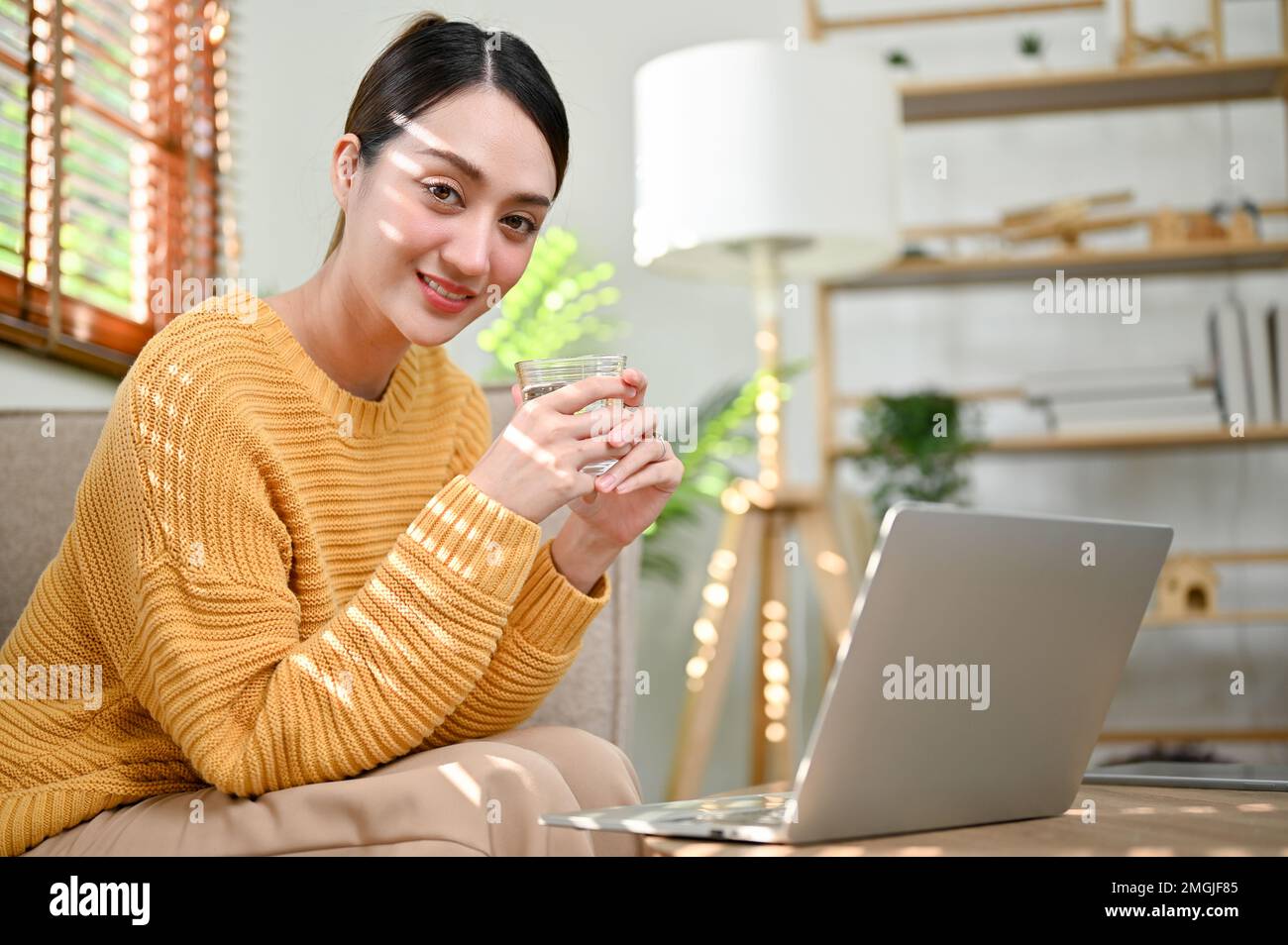 Attractive millennial Asian woman in casual clothes smiling, looking at ...