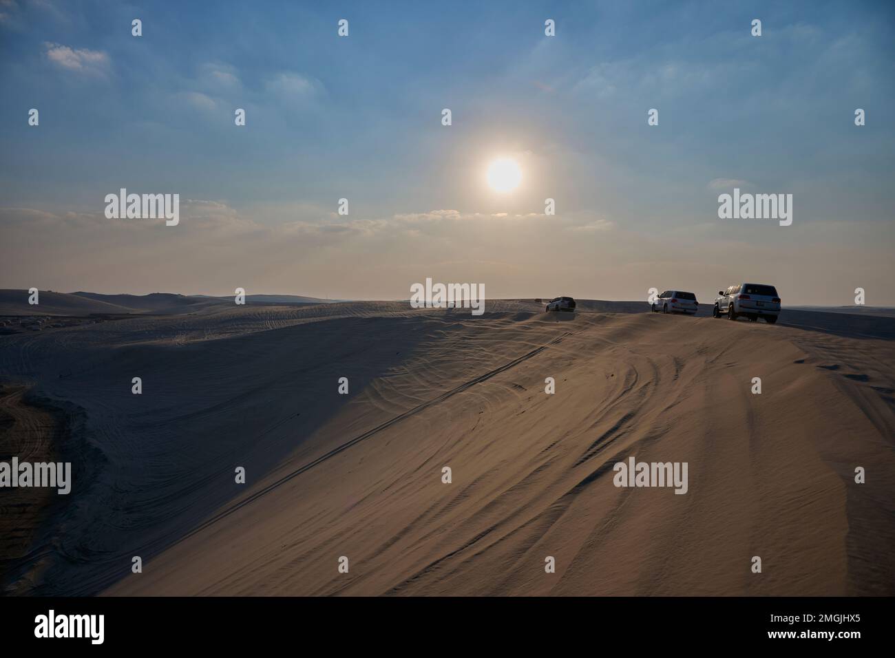 Watching people riding in 4x4's racing over the dunes near Doha, where ...