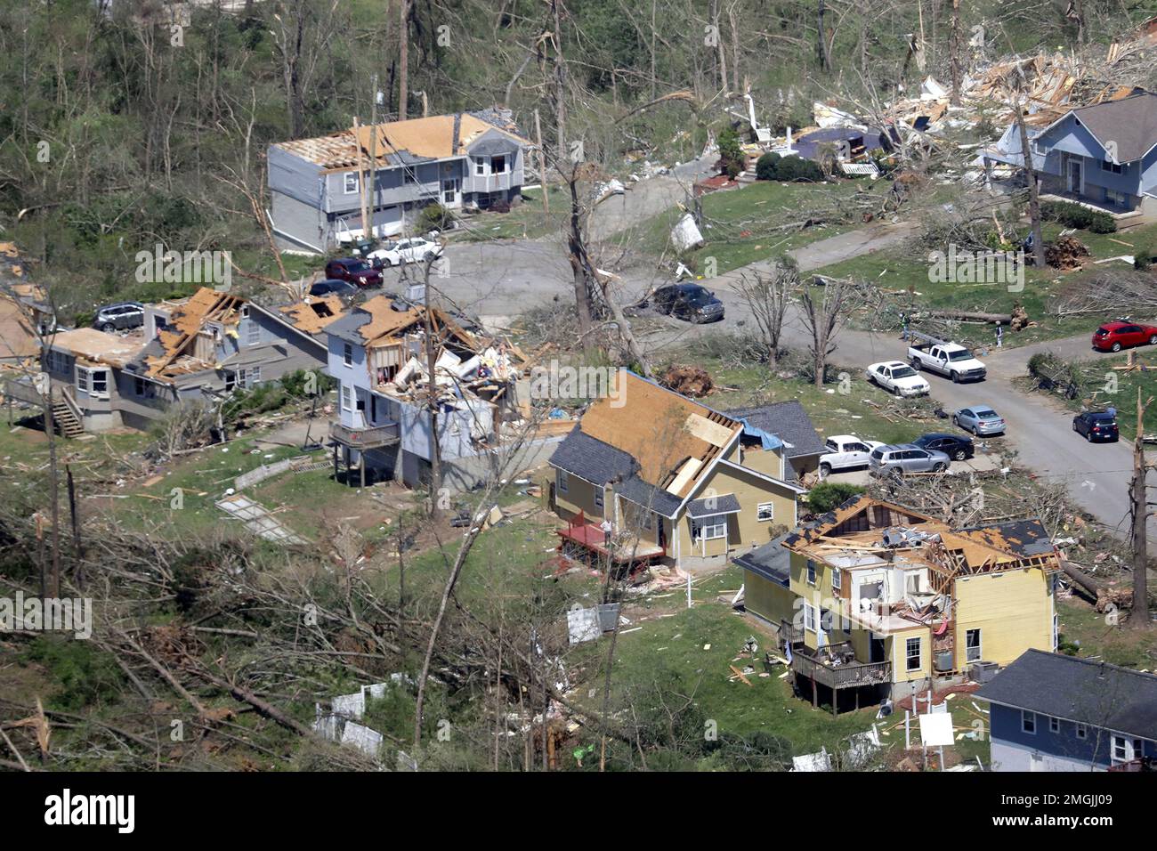Fallen trees and damaged homes line a street Tuesday, April 14, 2020 ...