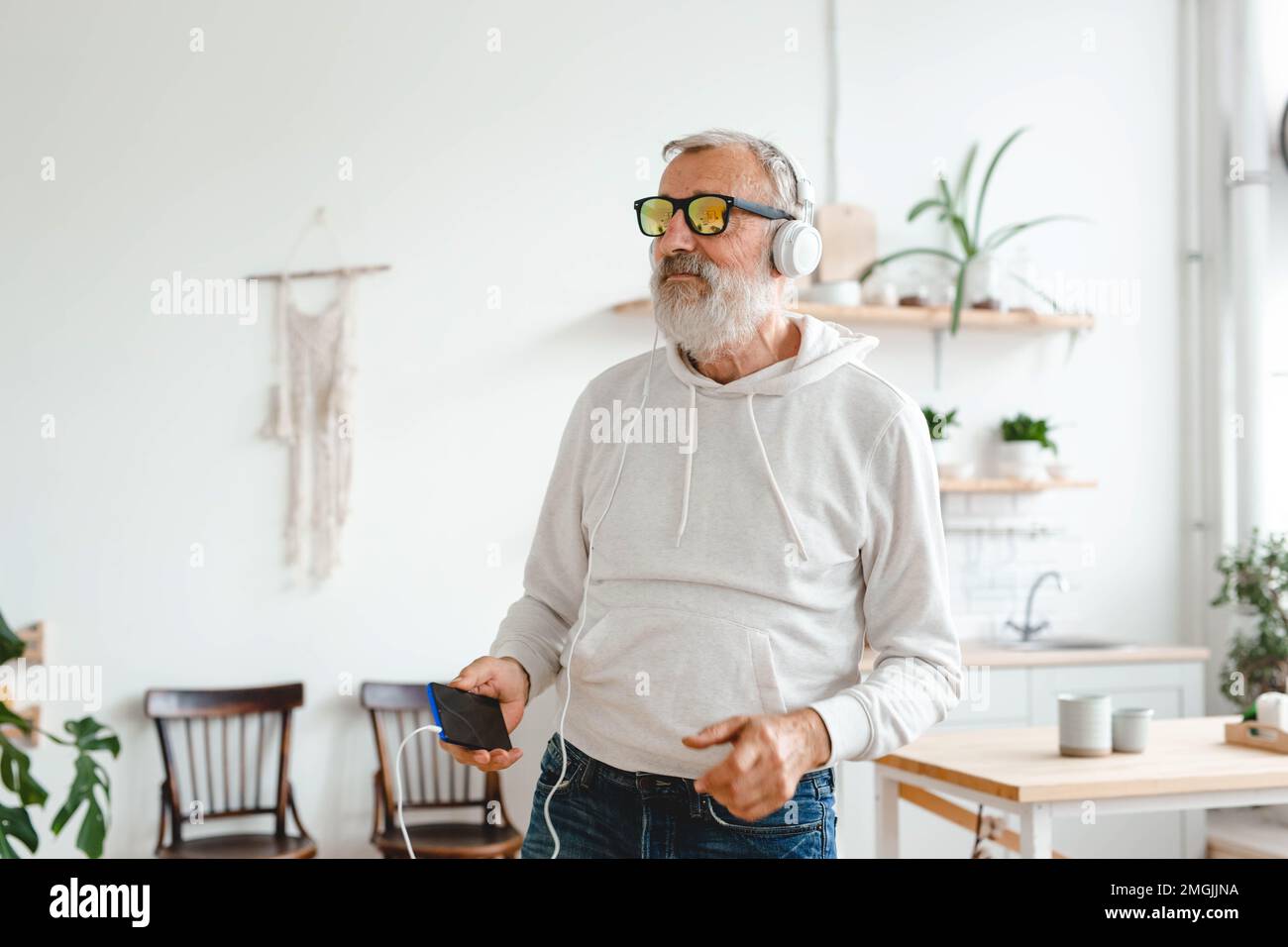 Happy Senior Man Dancing While Listening To Music With Headphones