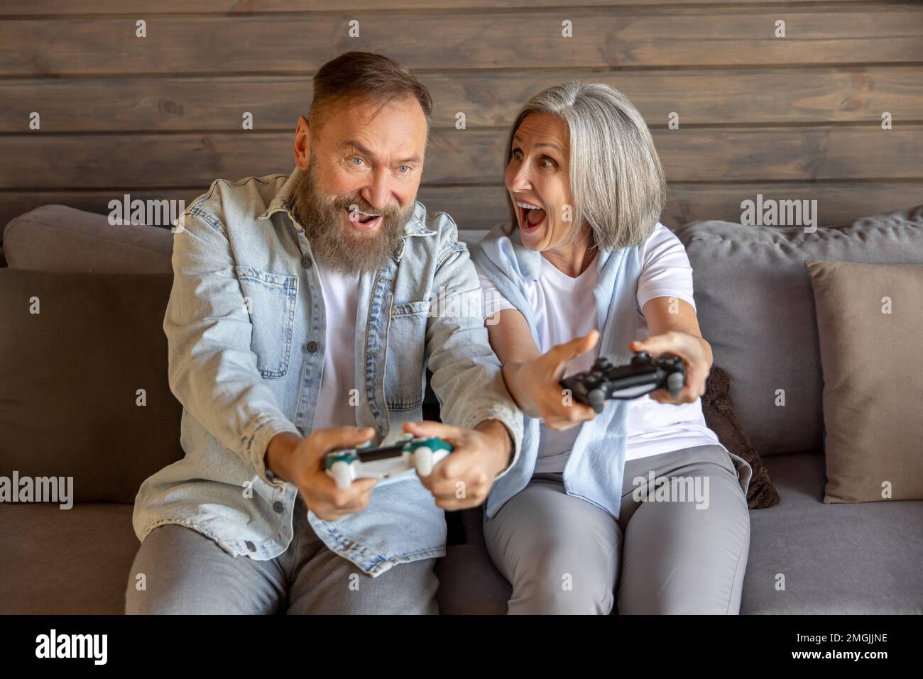 Mature couple playing video games and looking excited Stock Photo - Alamy
