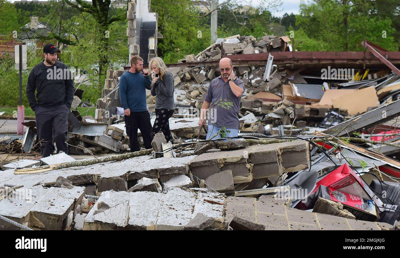 Employees of an auto parts store look over damage to their building ...