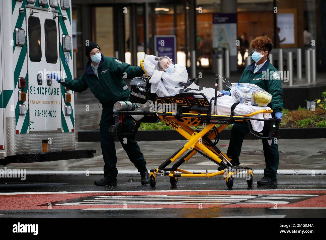 A patient on oxygen is wheeled out to an ambulance by medical workers ...