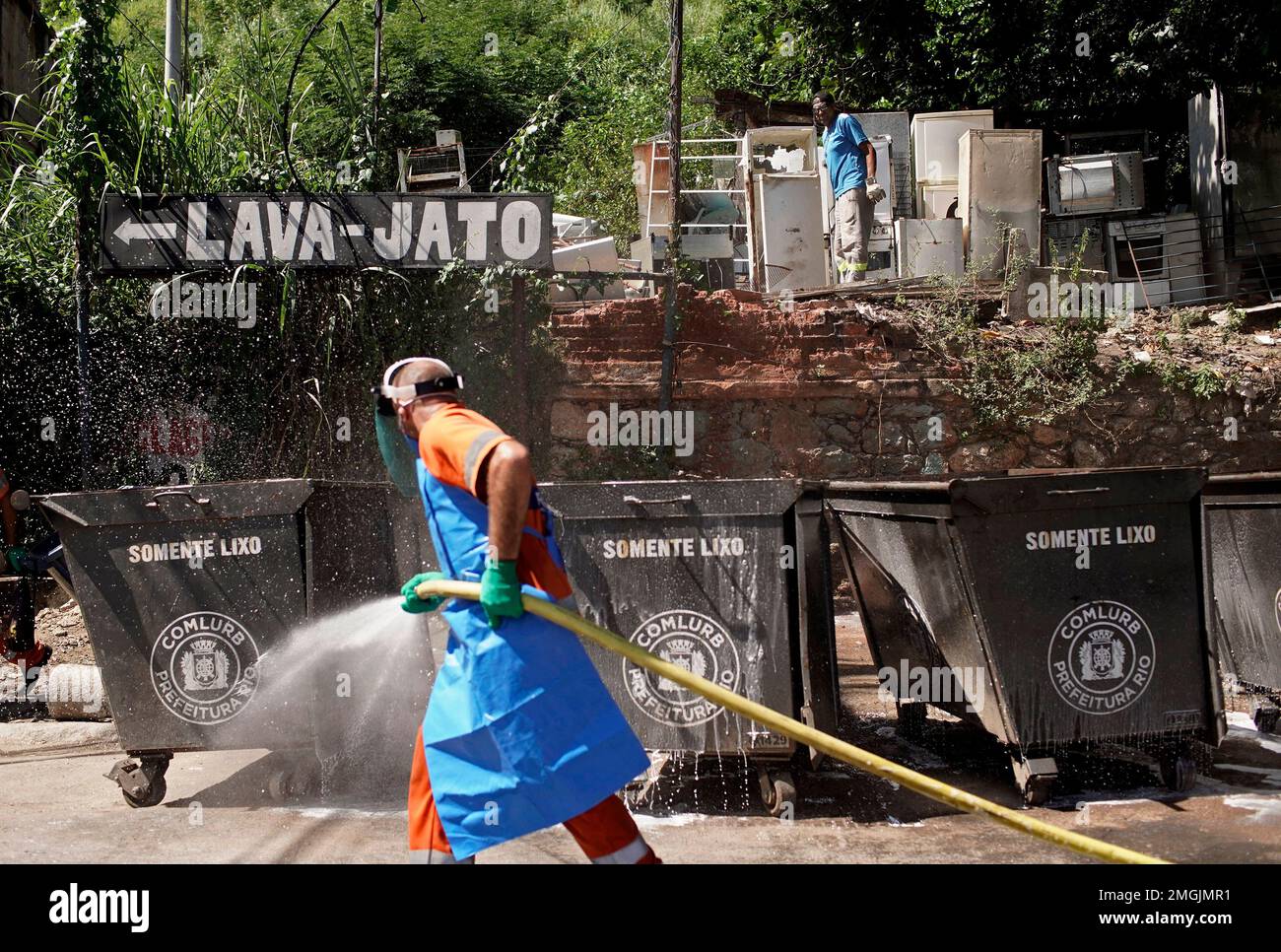 A resident watches a city worker disinfect the Andarai favela, in an ...