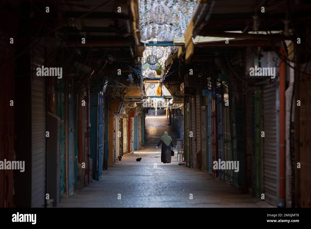 A woman walks down an alley in a closed market during government ...