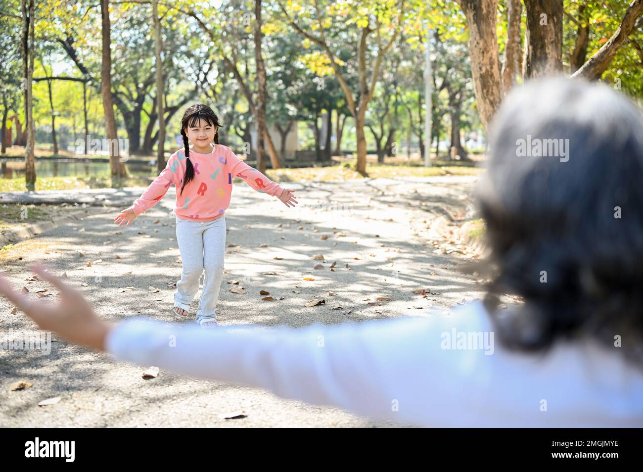 An adorable Asian little girl, granddaughter running to her grandmother ...