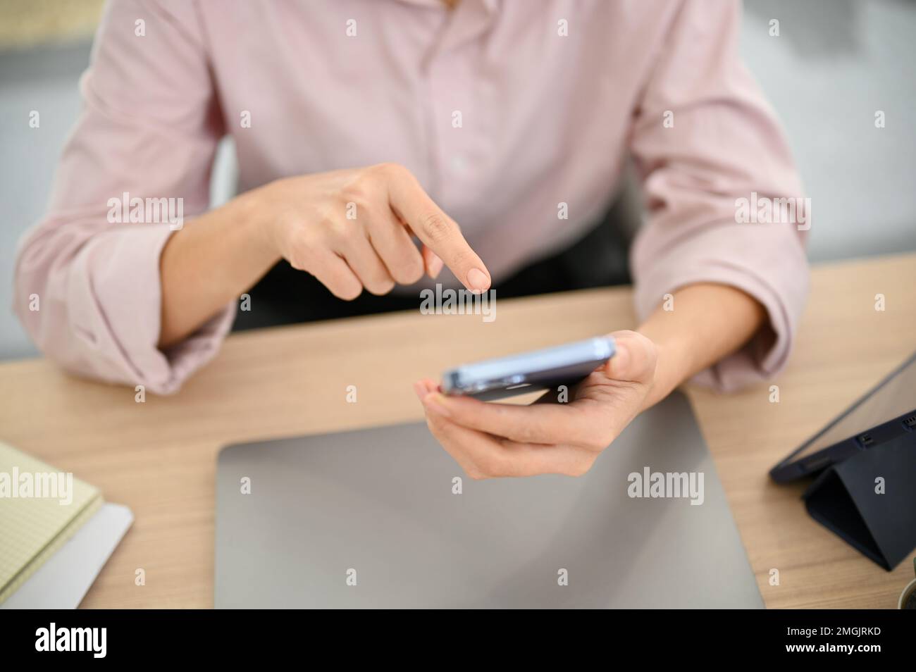 Top view of a female office worker using a smartphone at her desk ...