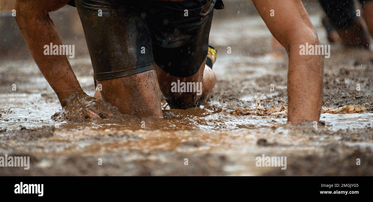 Mud race runners.Crawling,passing under a barbed wire obstacles during ...