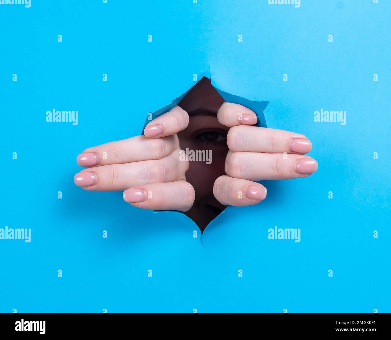 Female hands sticking out through a hole on a blue background Stock ...
