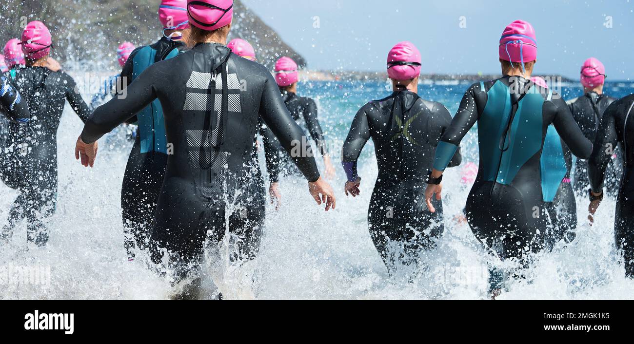 Group triathlon participants running into the water for swim portion of ...