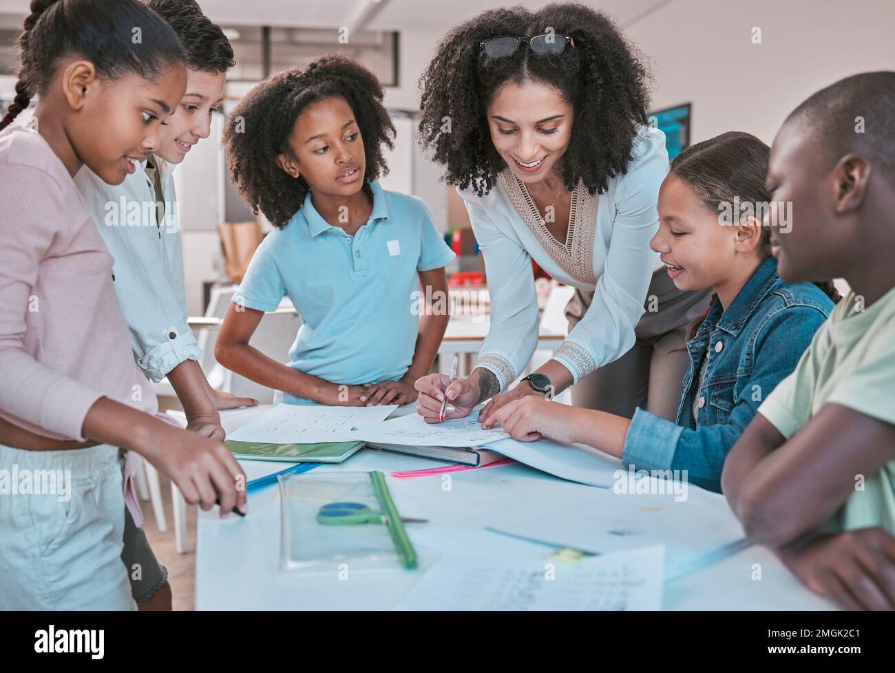 Female teacher in classroom with students, helping learner with ...