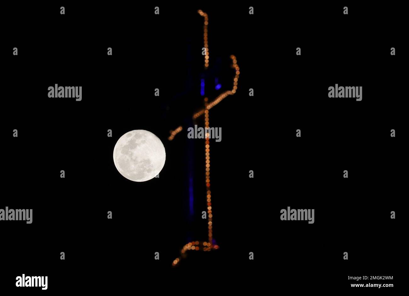 A full moon is seen behind a cross on top of a Catholic church in ...