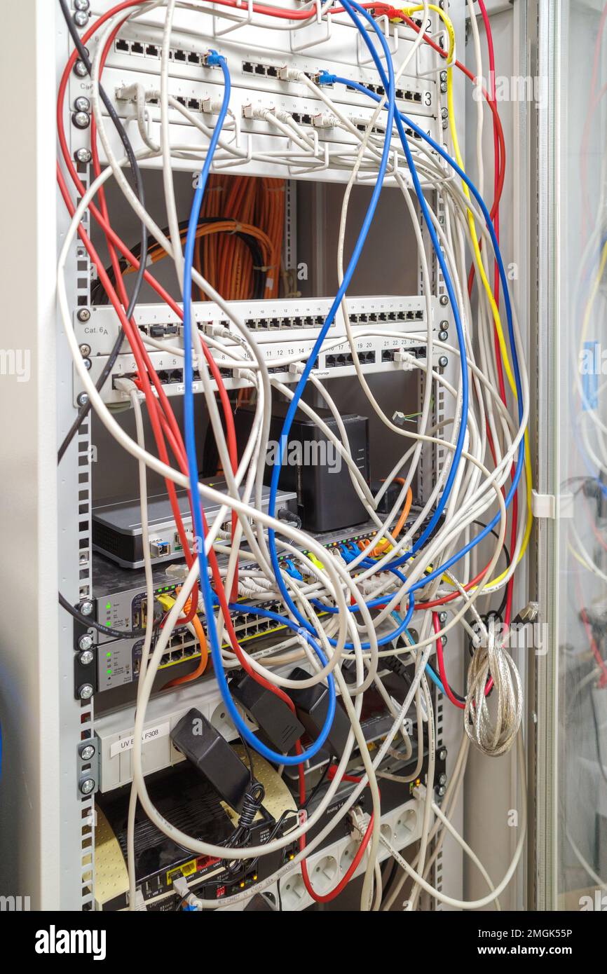 in the server rack many different colored network cables are connected to the network switches ...