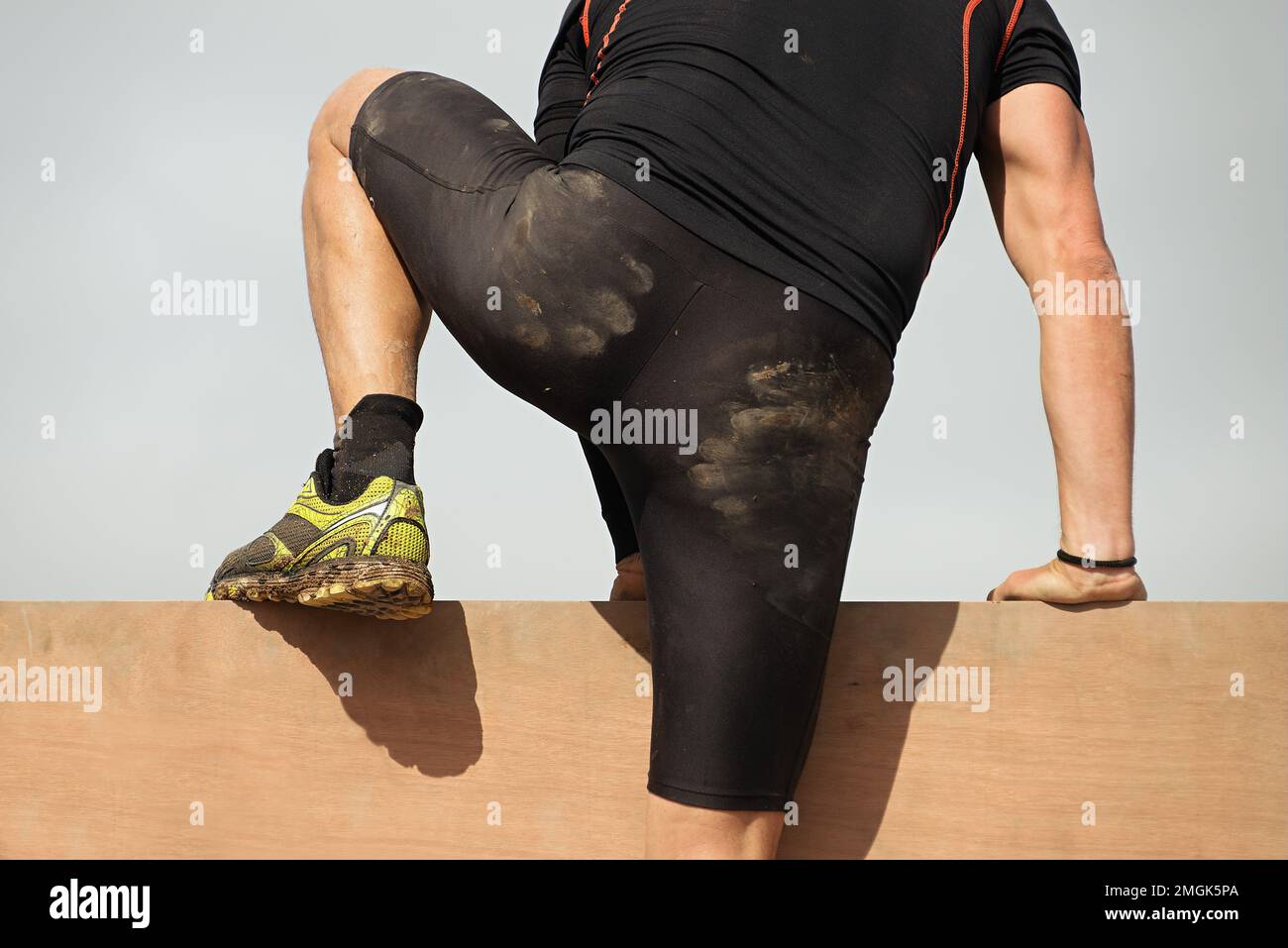 Mud race runners, participant jumps over obstacles Stock Photo - Alamy