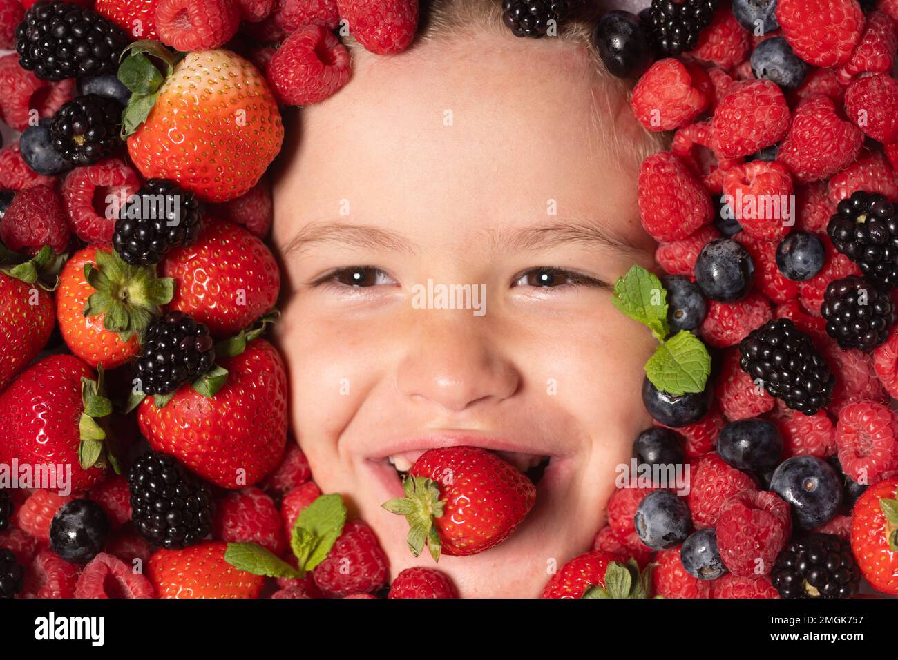 Fruits for kids. Child face with berry frame, close up. Berries mix ...