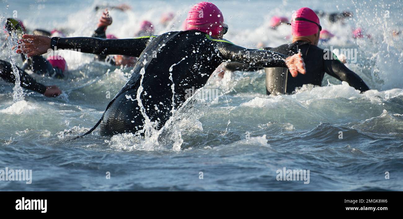 Group triathlon participants running into the water for swim portion of ...
