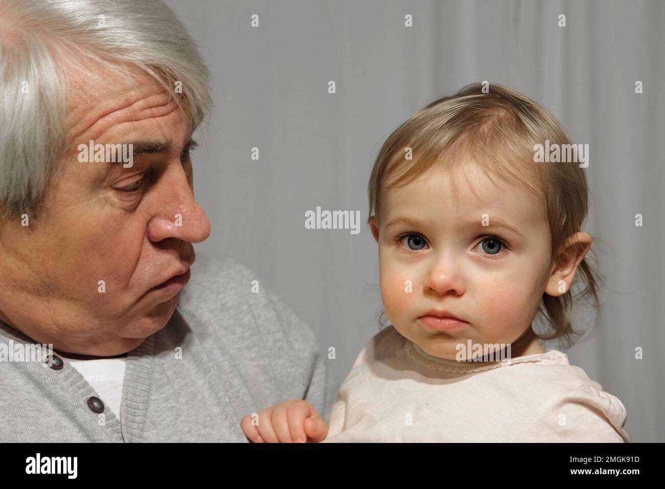 Gray Haired Old Man holds his little granddaughter in his hands. Family ...