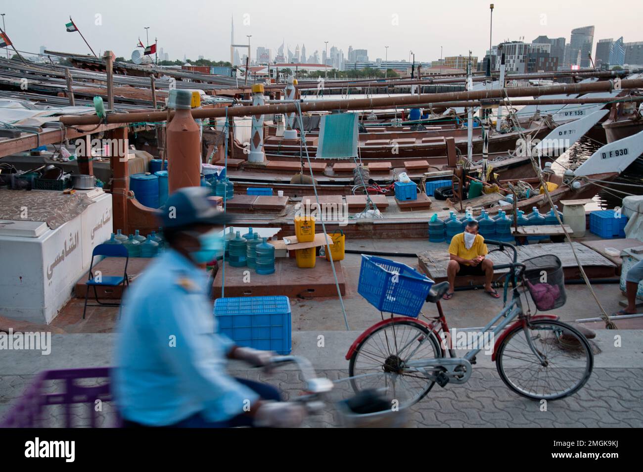 A security guard on a bicycle wearing a mask rides past a fisherman in ...