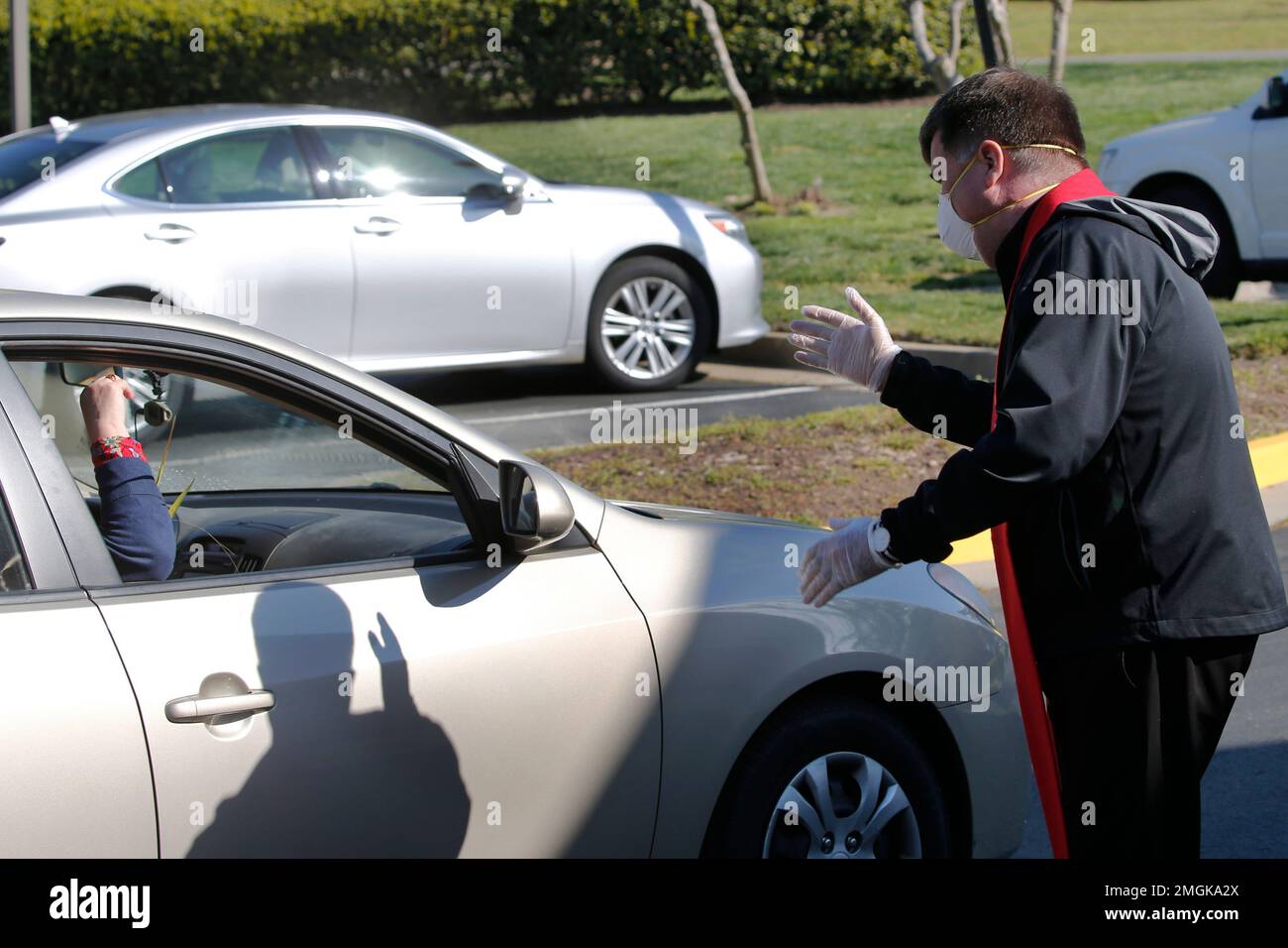 Catholic priest Father Mike Renninger, wearing mask and gloves prays ...