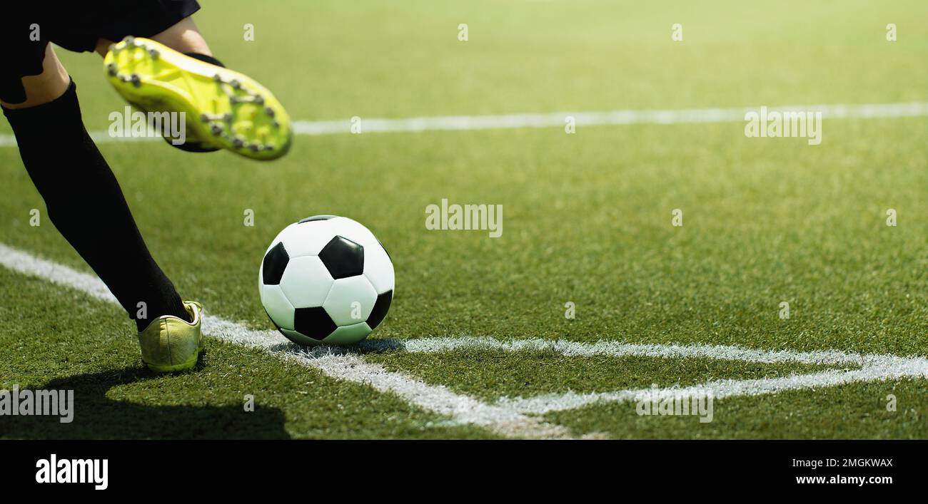 Foot of a child football player and ball on the football field, kicking ...