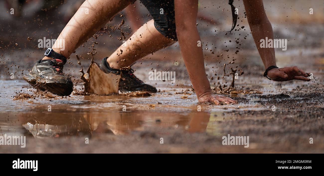 Mud race runners.Crawling,passing under a barbed wire obstacles during ...