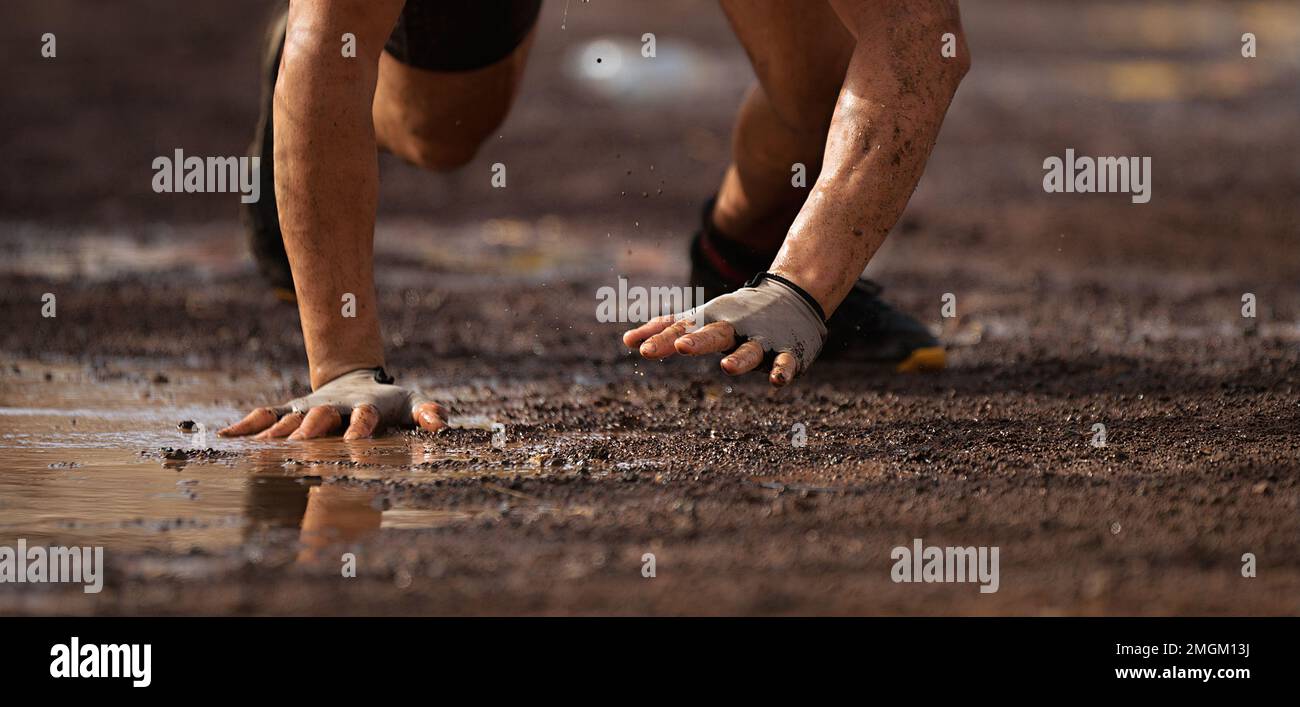 Mud race runners.Crawling,passing under a barbed wire obstacles during ...