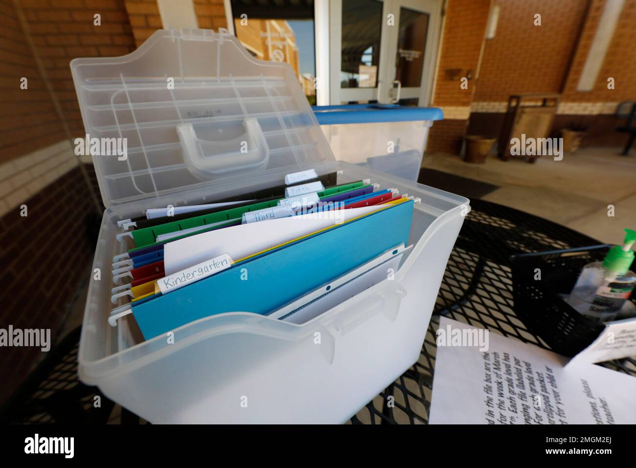 Grade-appropriate paper homework packets are arranged in a plastic file ...