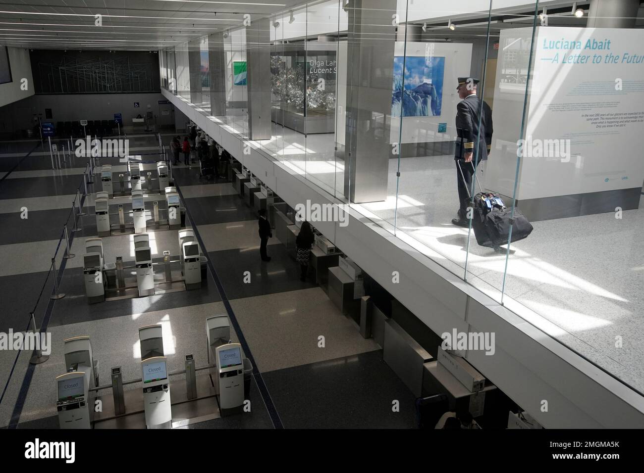 A pilot looks over sparse crowds at a check-in counter at the United ...
